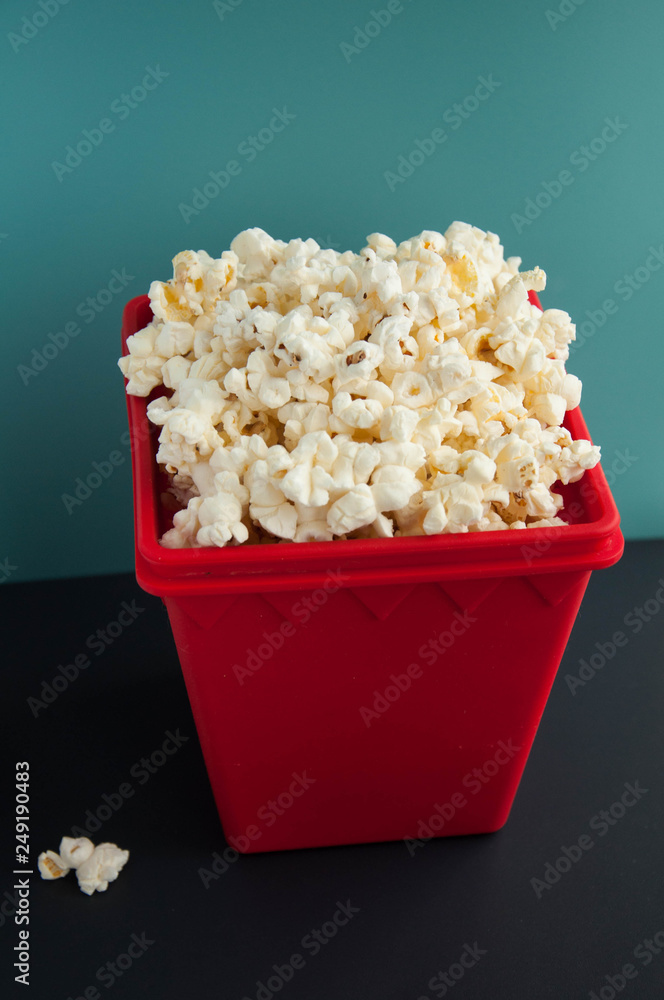 Popcorn in a red container on a white and black background. Snacks for ...