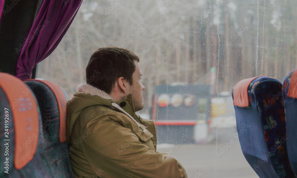The guy looks out the window in the back of the bus. The guy went on a ...