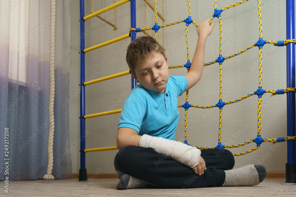 Sad child with a broken arm in the home environment . The cast on the ...