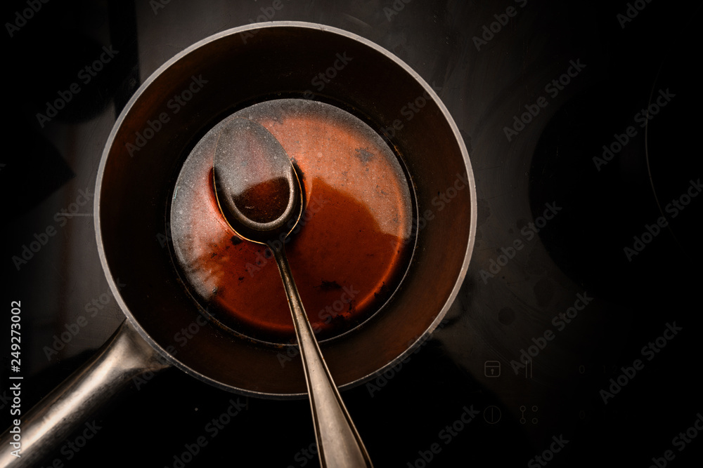 pot and spoon with beef stock while cooking a red wine morel sauce on a ...