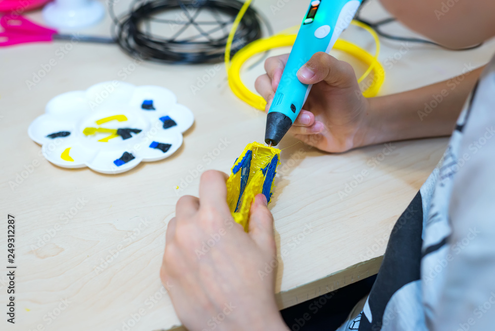 Boy making a stick figure creating new 3d object with 3d printing pen ...