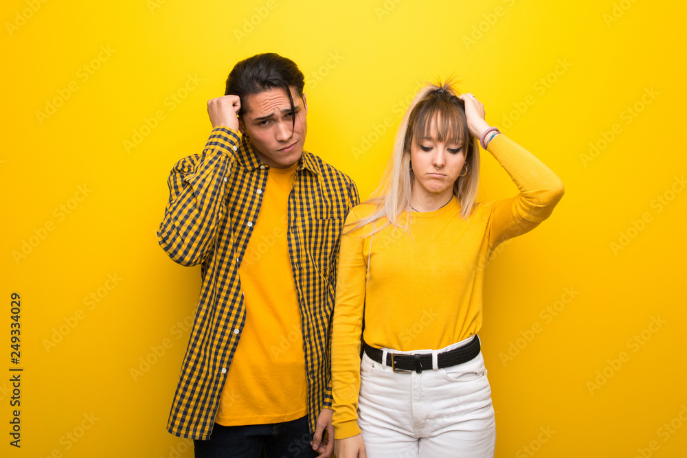 Young couple over vibrant yellow background with an expression of ...