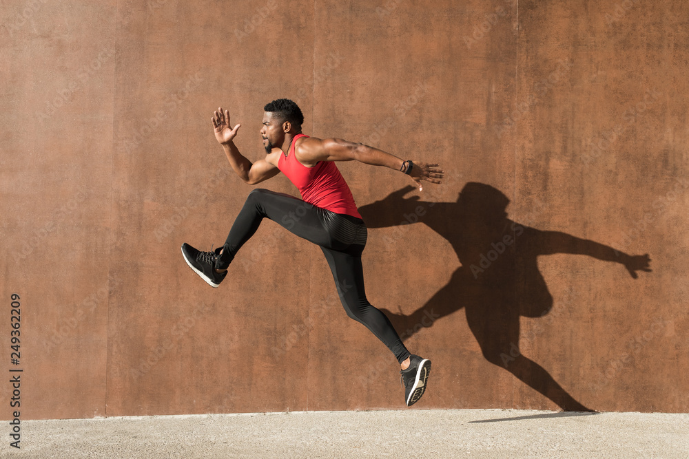 Young black man running and jumping casting shadow on a wall. Stock ...