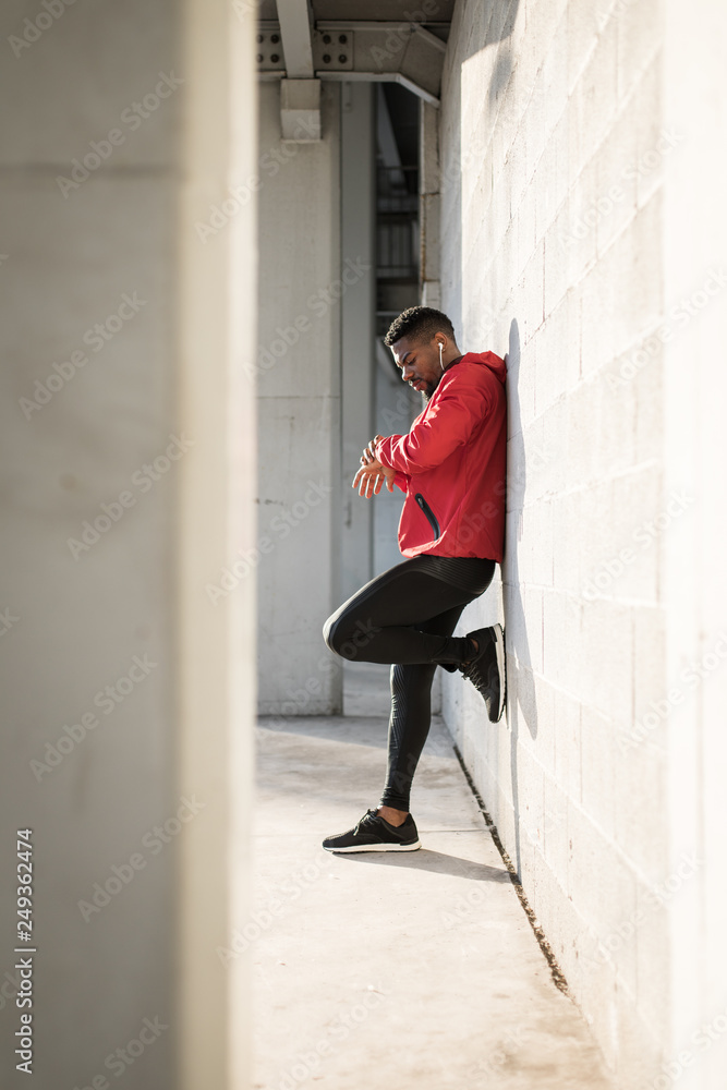 Black runner taking a break for timing and checking running workout ...