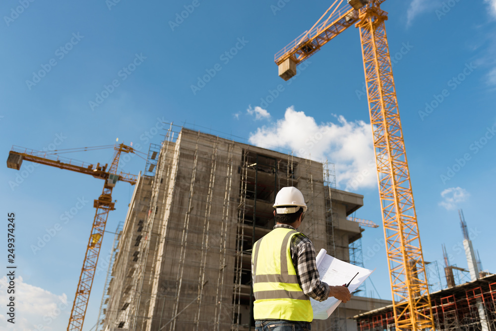 Civil engineer checking work with construction drawing at building site ...