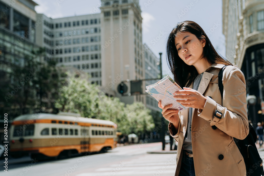 Young asian female tourist checking out the sights while reading paper ...