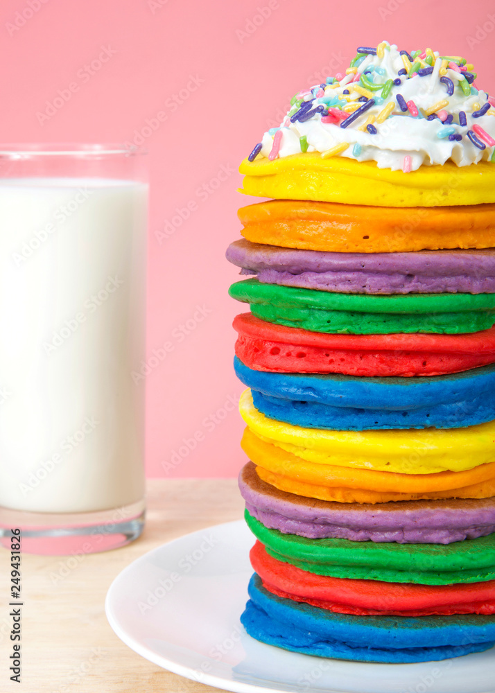 Stack of bright colorful pancakes topped with whipped cream and candy ...