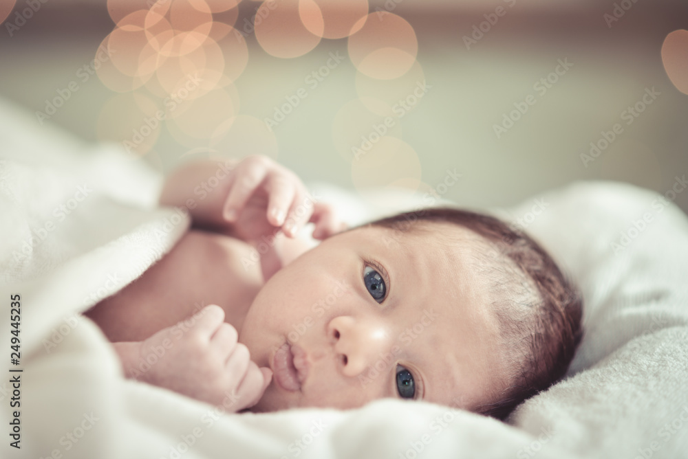 Newborn portrait on the white blanket in doubts face with bokeh ...