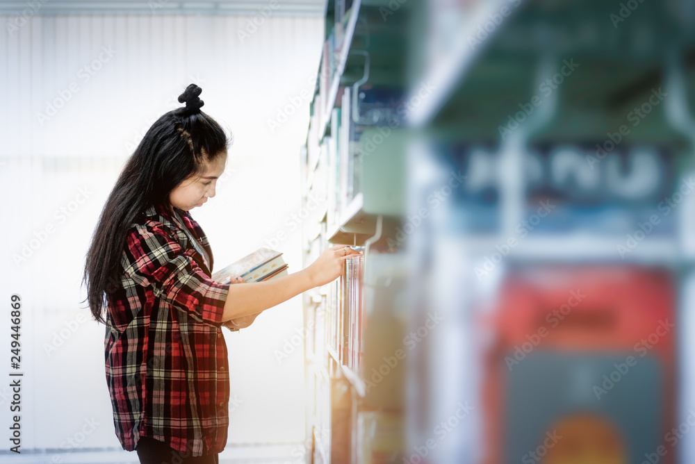 Asian Student searching for textbook in the bookshelf in the ...