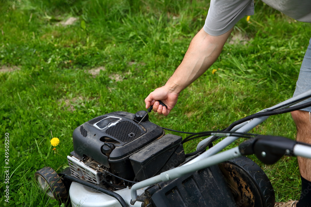 Starting an lawn mower to mow lawns. Stock Photo | Adobe Stock