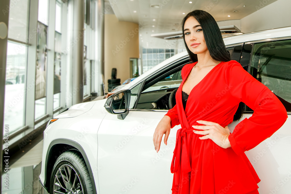 Beautiful girl next to an expensive car in a car dealership. Concept ...