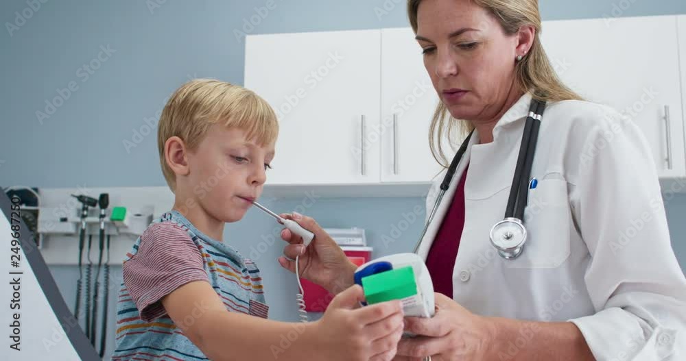 Female pediatrician using digital thermometer to check temperature of ...