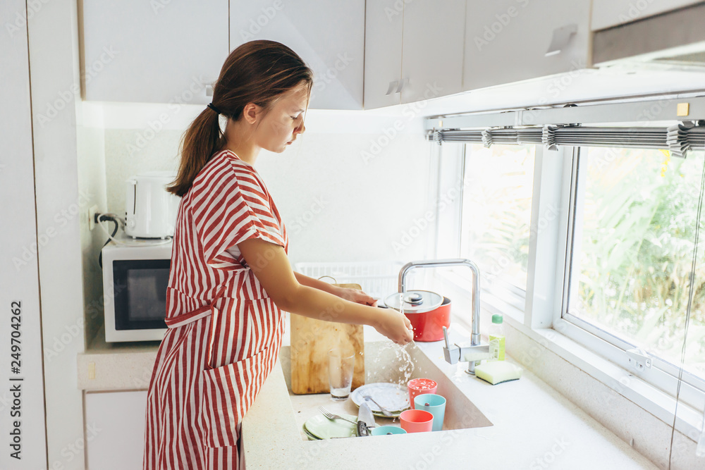 Teenage girl washing dishes in the kitchen Stock Photo | Adobe Stock