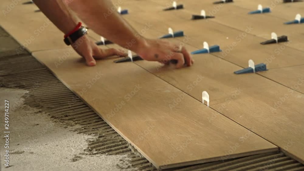 Skilled professional construction worked installing new floor tiles ...