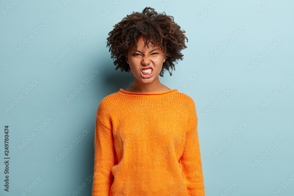 Irritated black young cute woman frowns face, clenches teeth with anger ...