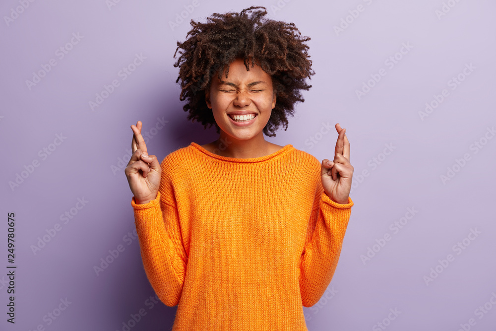 Positive black woman with Afro hairstyle, closes eyes, makes praying ...