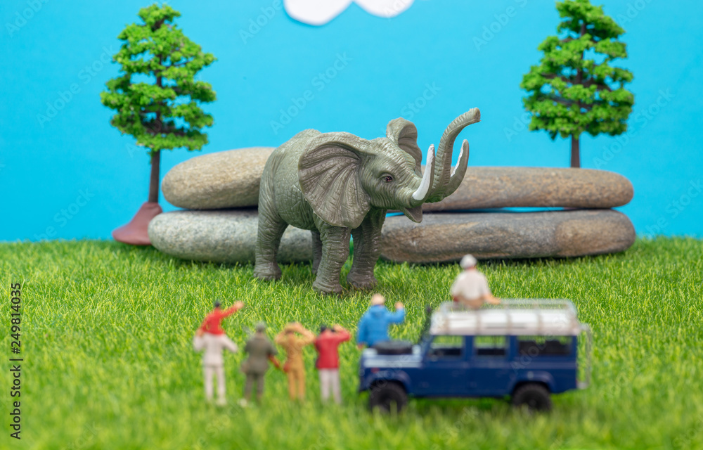 Miniature toys of a group of people on safari trip watching loxodonta ...