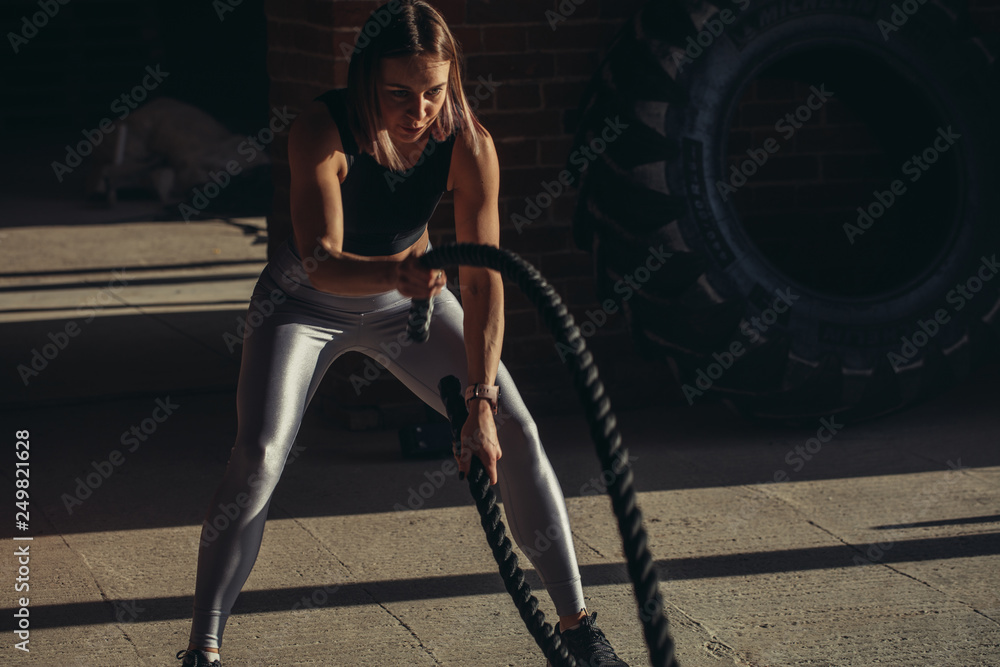 Young well trained muscular female athlete standing with jumping rope ...
