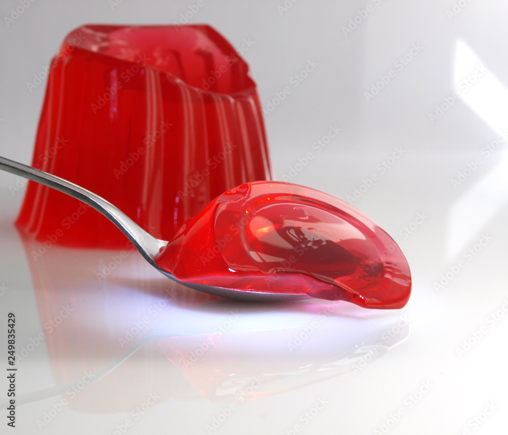 spoon full of sweet jelly pudding strawberry flavor over white ...