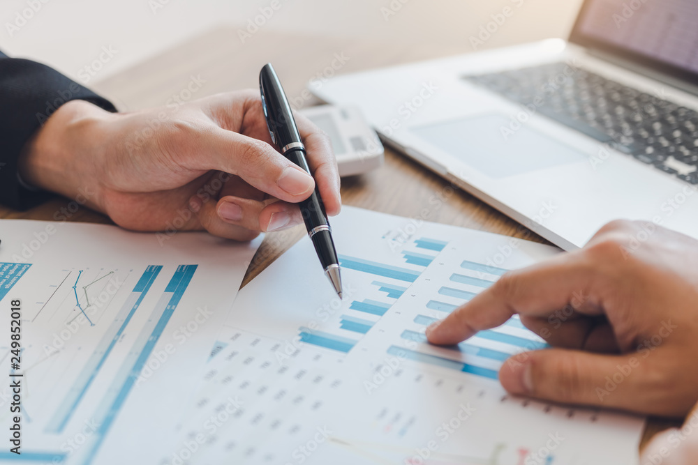 Two businessmen are pointing to the company cost graph and then ...