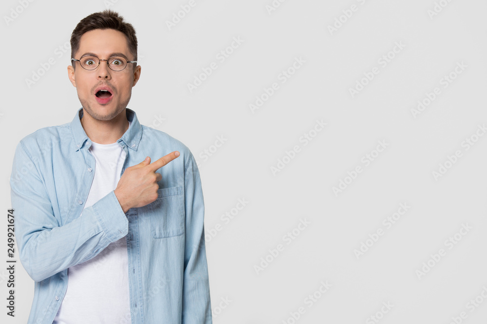 Shocked stunned young man nerd pointing finger aside at copyspace Stock ...