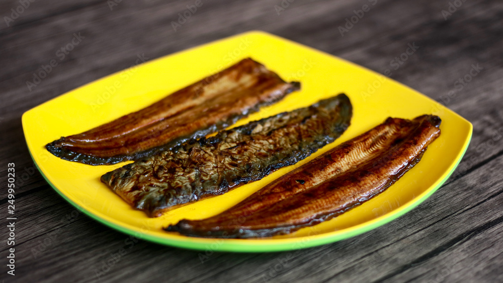 Eel fish or unagi on yellow plate with wood background. Ready to cook ...