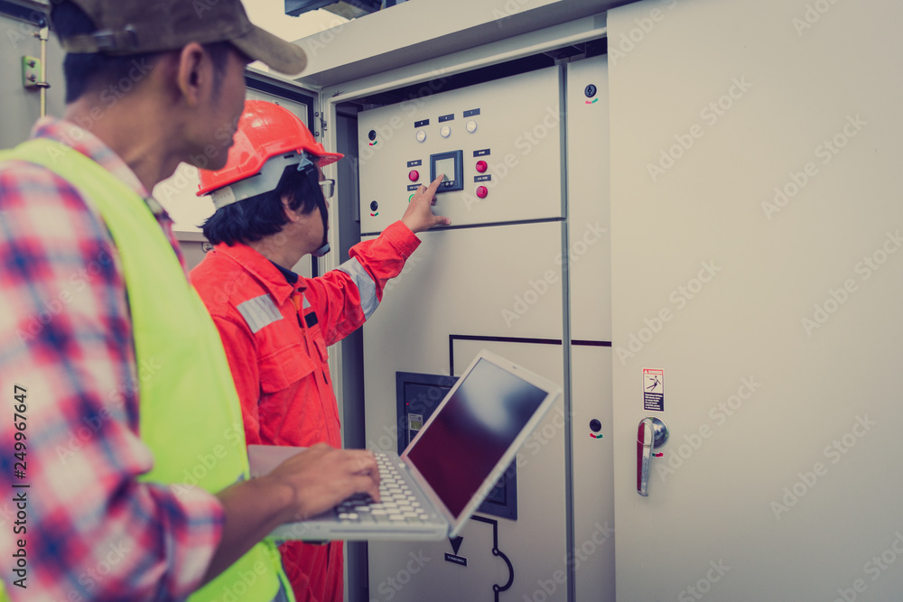 engineer or electrician holding laptop for inspect and checking main ...