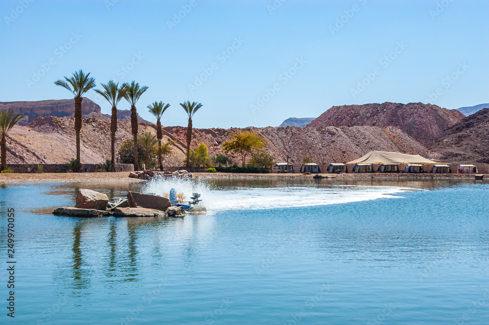 Timna Lake surrounded by camping areas, resting zones, growing palms ...
