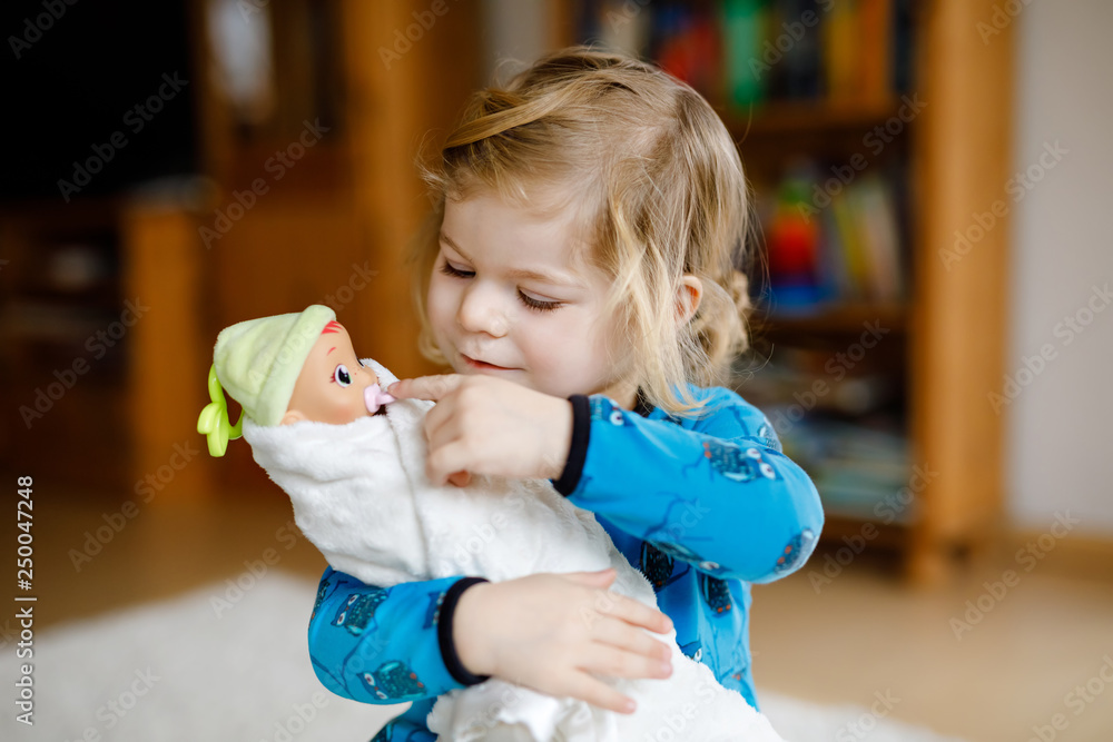 Adorable cute little toddler girl playing with doll. Happy healthy baby ...