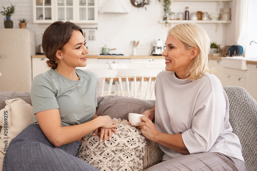 Sideways image of cute charming young female visiting her middle aged ...