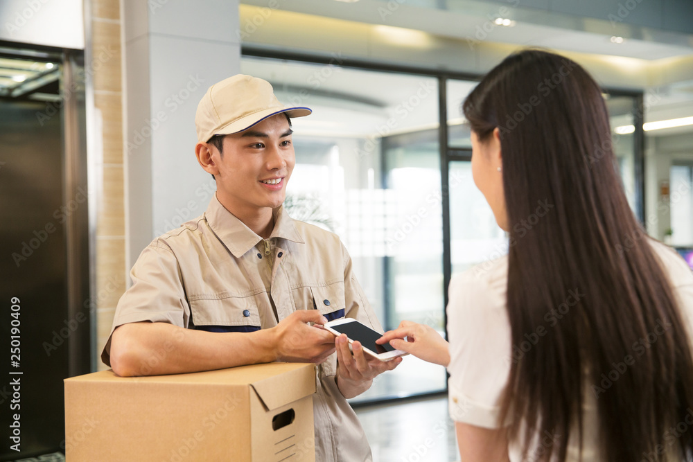 Delivery man showing smartphone to woman at reception Stock Photo ...