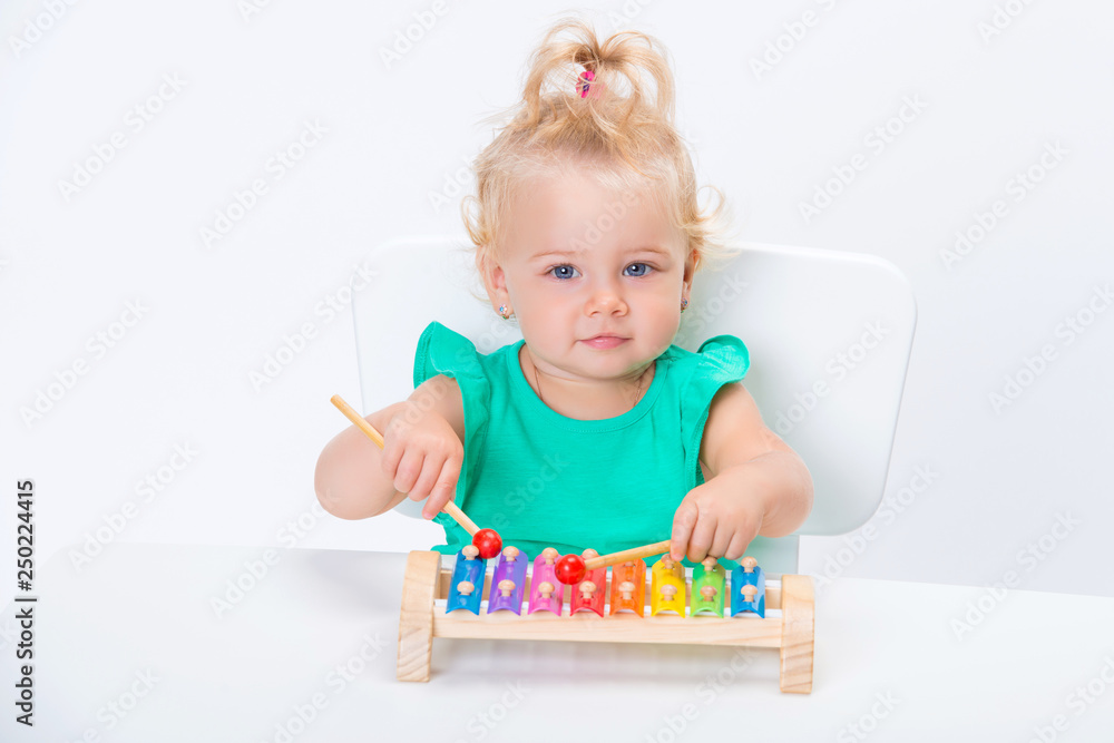Cute smiling child little blonde baby girl playing with musical toy ...