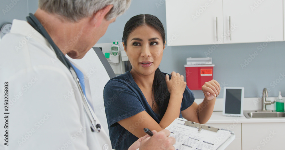 Woman with rotator cuff injury listening to doctor explain treatment ...
