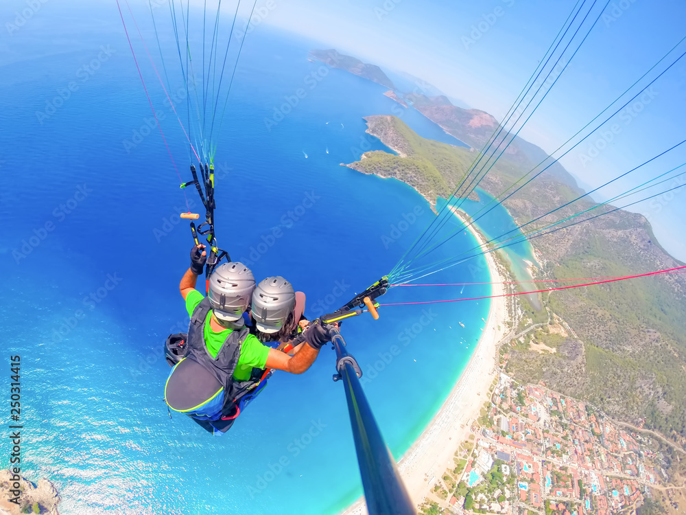 Paragliding in the sky. Paraglider tandem flying over the sea with blue ...