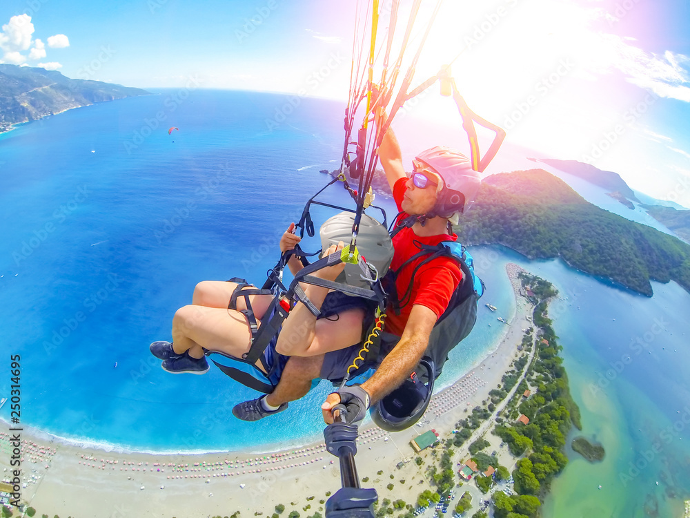 Paragliding in the sky. Paraglider tandem flying over the sea with blue ...