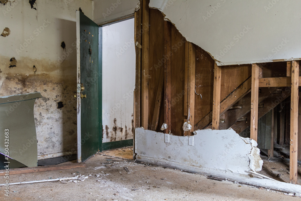 Front door left ajar in abandoned home with exposed framing and torn ...
