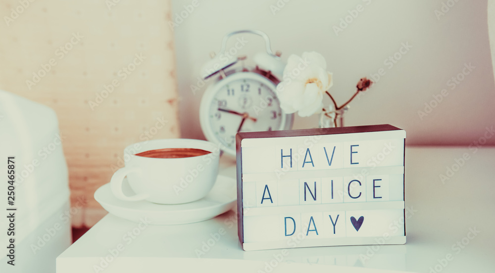 Have a nice day message on lighted box, alarm clock, cup of coffee and ...