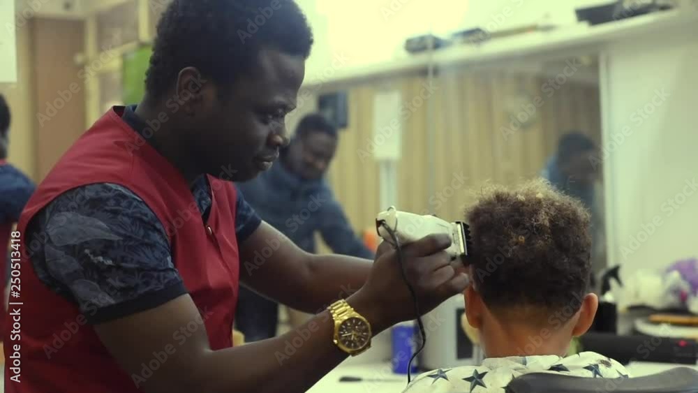Boy in the african barbershop. Cute mixed boy makes a haircut in the ...