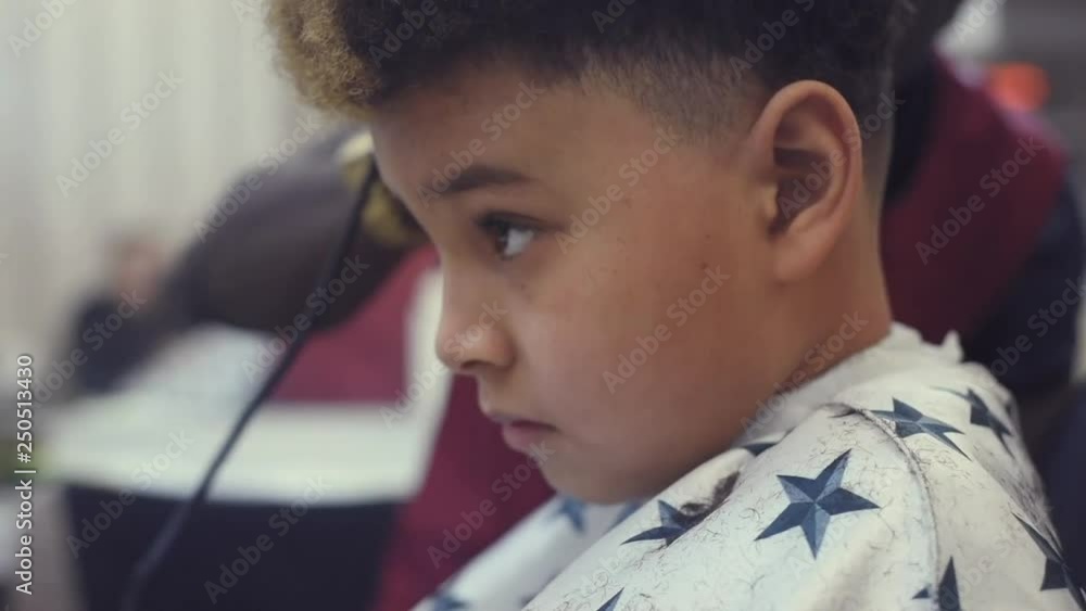 Boy in the african barbershop. Cute mixed boy makes a haircut in the ...