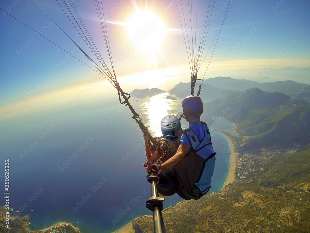 Paragliding in the sky. Paraglider tandem flying over the sea with blue ...