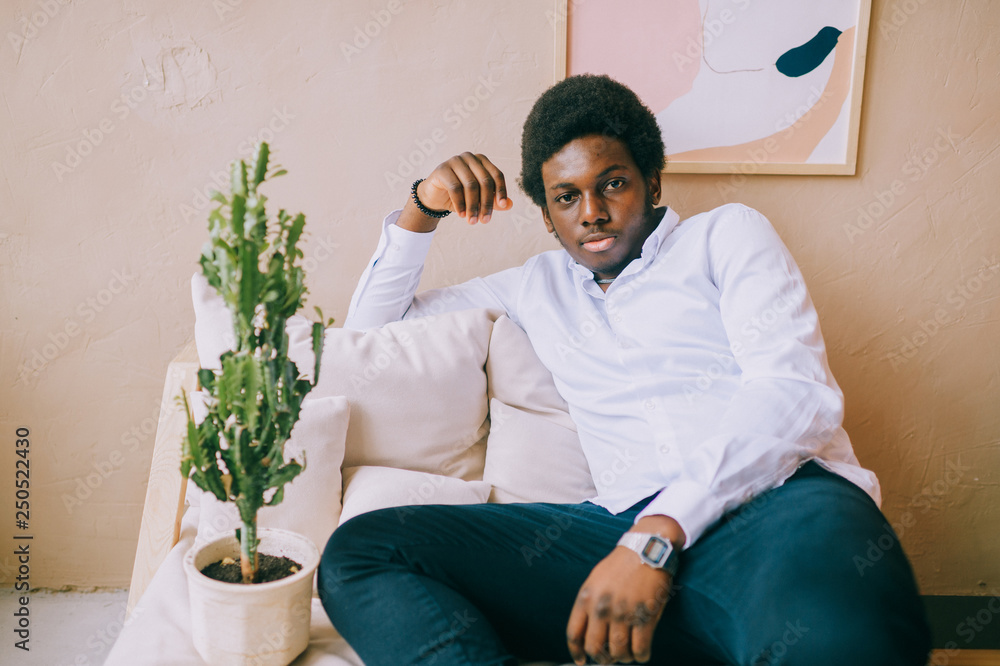 Lifestyle portrait of handsome young african black man sitting in chair ...