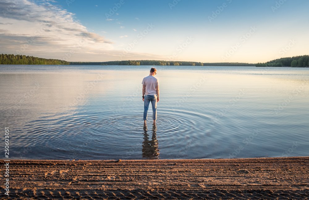 Man standing in water at beautiful summer day with idyllic lake and ...