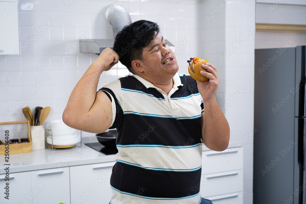 Young fat man eating hamburger and show his muscle Stock Photo | Adobe ...