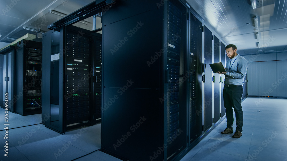 Bearded IT Specialist in Glasses is Working on Laptop in Data Center ...