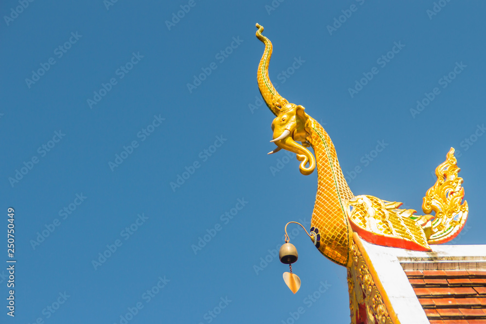 Beautiful golden naga sculptures on the church roof under the blue sky ...