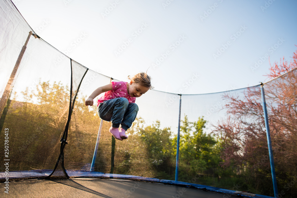 Child jumping high in the air on a trampoline Stock Photo | Adobe Stock