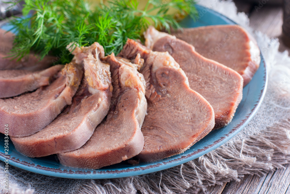 Chopped boiled beef tongue on a plate with fresh herbs and pickled ...