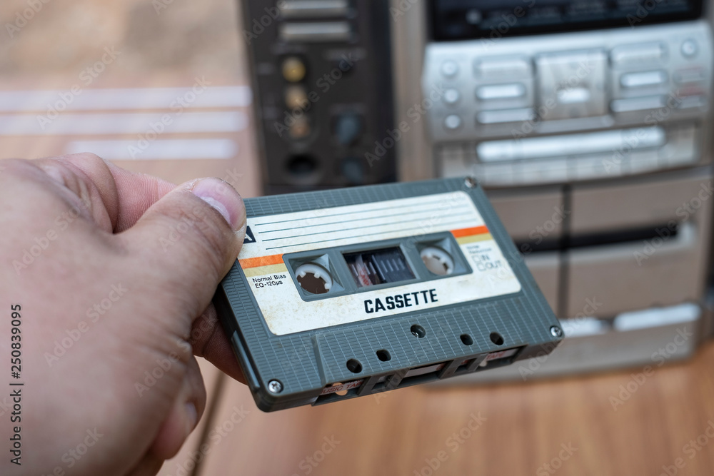 Man hand putting cassette into old fashioned audio tape player on top ...
