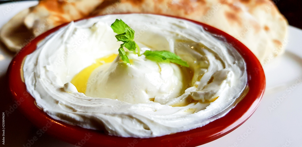 Foto de A bowl of Labneh, popular arab yoghurt cream cheese dip, with mint leaves do Stock ...