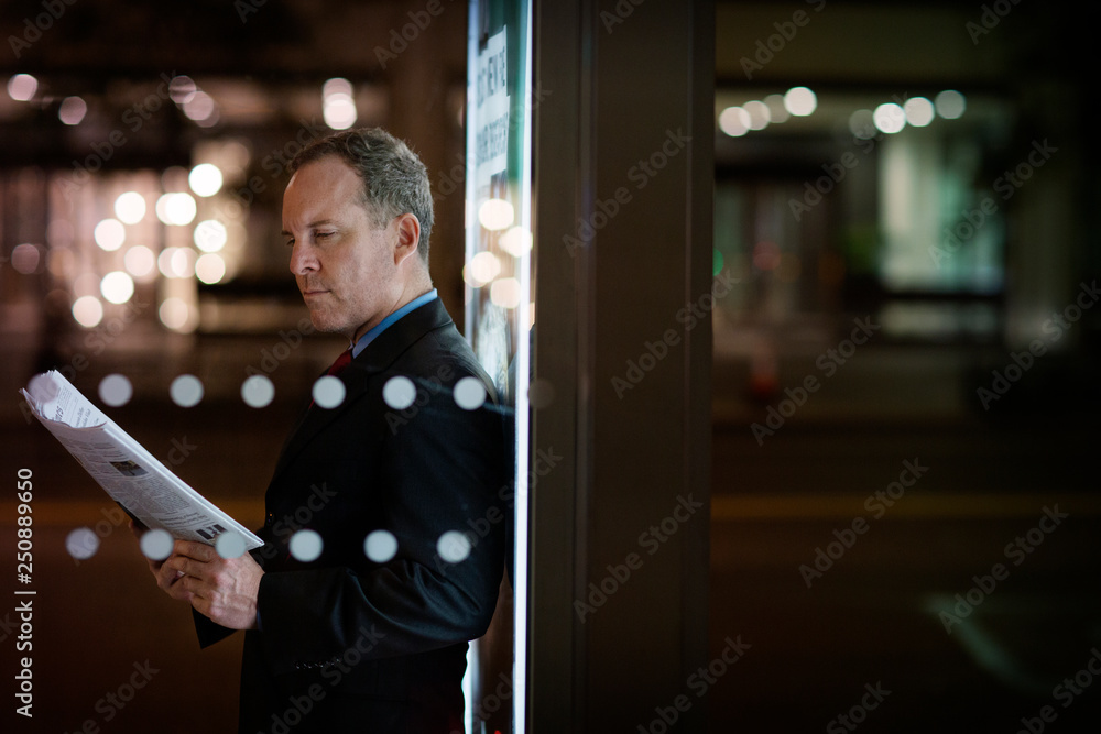 Man leaning against post and reading newspaper Stock Photo | Adobe Stock